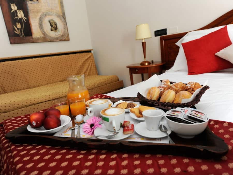 Bandeja de café da manhã bem organizada com doces, café e frutas em um quarto de hotel.