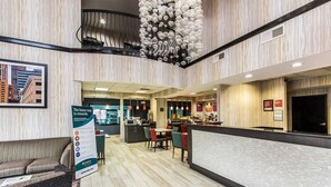 Um hall de hotel com balcão de recepção, área de estar e escadaria.