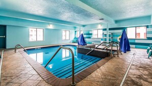 Piscina interior com água azul cristalina, piso azulejado e paredes azuis.