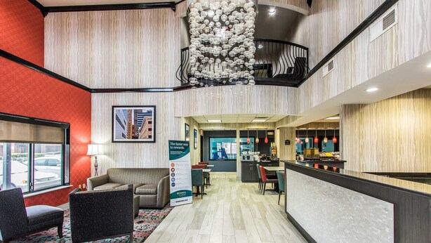 Um saguão de hotel com balcão de recepção, área de estar e escadaria.