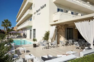 Um hotel com piscina, área de estar ao ar livre e uma placa que diz 'Mon Repos Palace'.