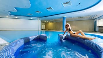 Uma grande piscina coberta com teto azul e chão em azulejos.