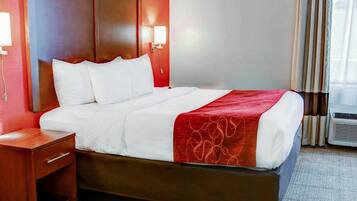 Quarto de hotel com cama, mesa de cabeceira, abajur e ar condicionado.