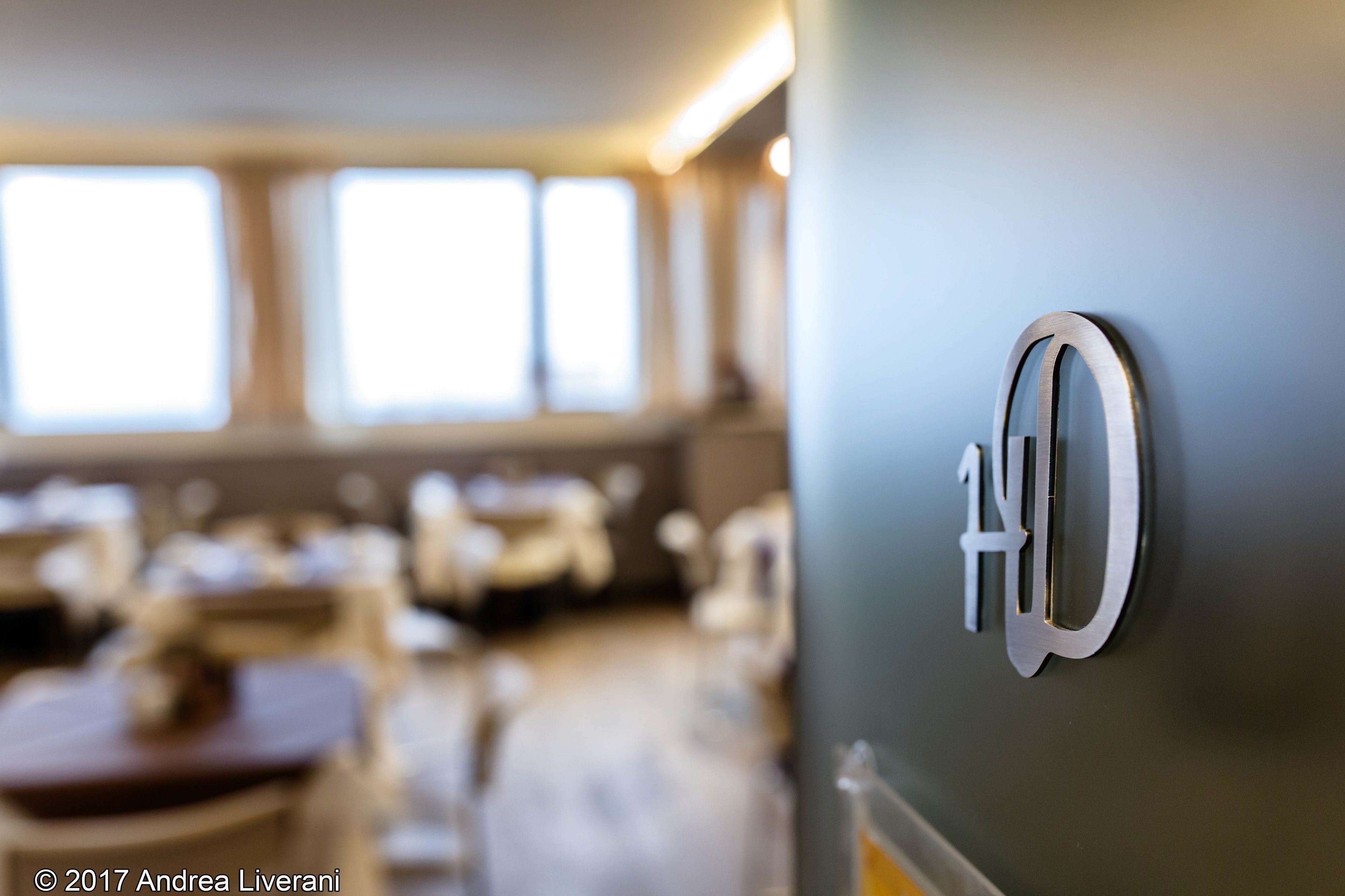 Visão interna desfocada de um hotel, com um grande sinal '10' na parede, possivelmente indicando números de quartos.