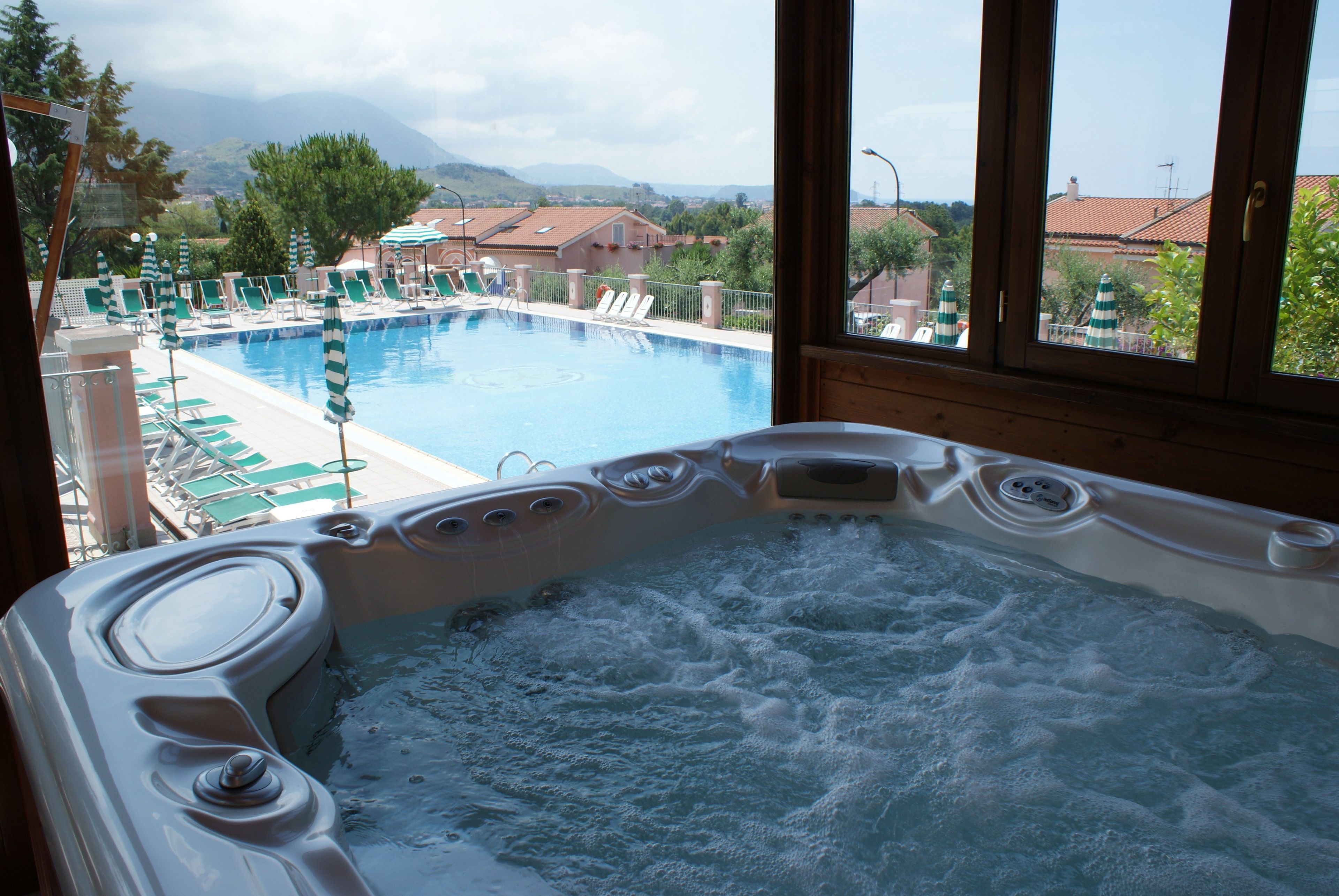 Uma banheira de hidromassagem com vista para uma piscina e espreguiçadeiras.