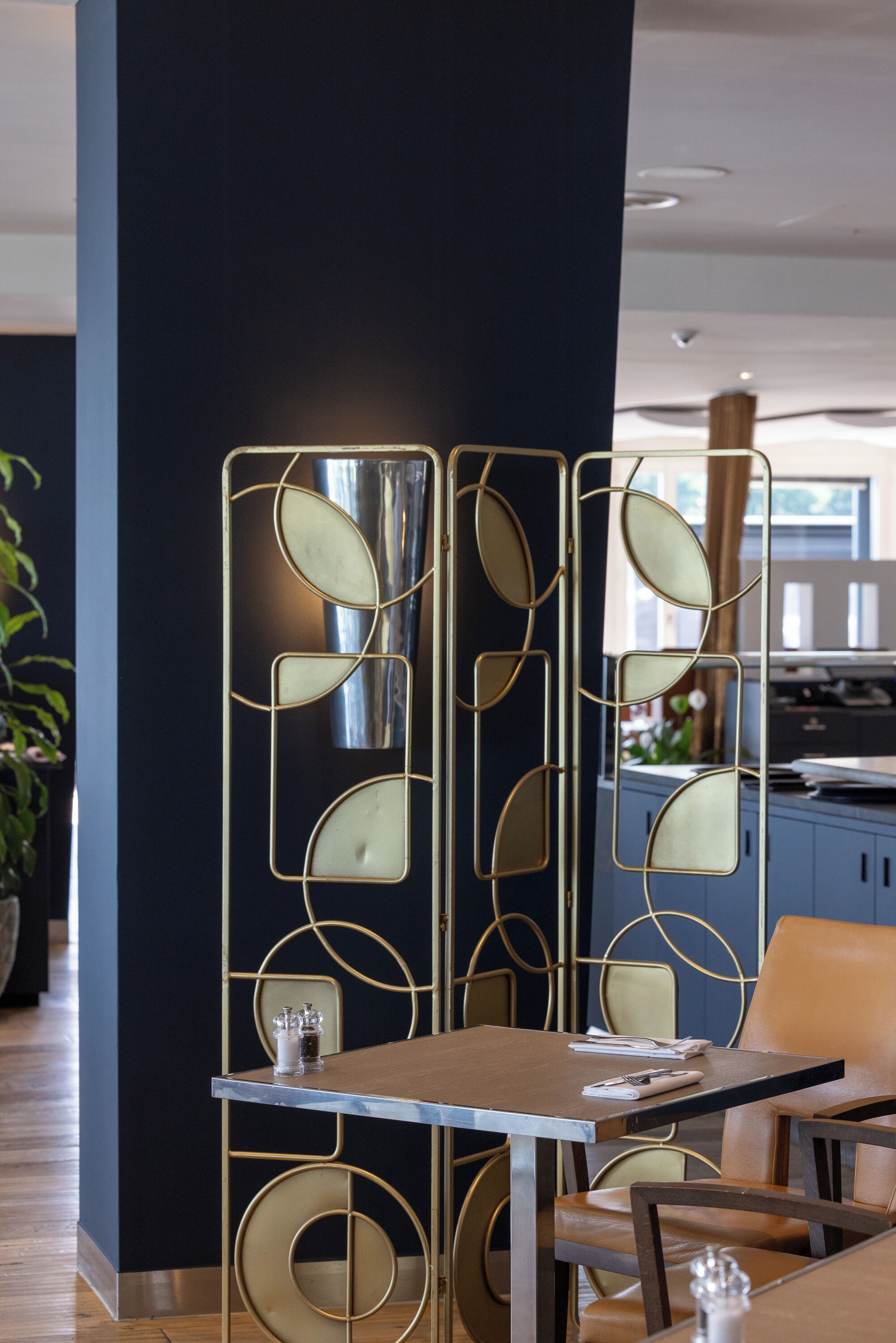 Uma área de refeições moderna com uma mesa, cadeiras e um divisória decorativa com espelhos circulares.