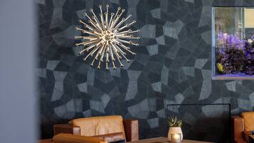 Um interior moderno com parede estampada em padrão geométrico, luminária decorativa, assentos em couro e uma pequena mesa com uma planta.