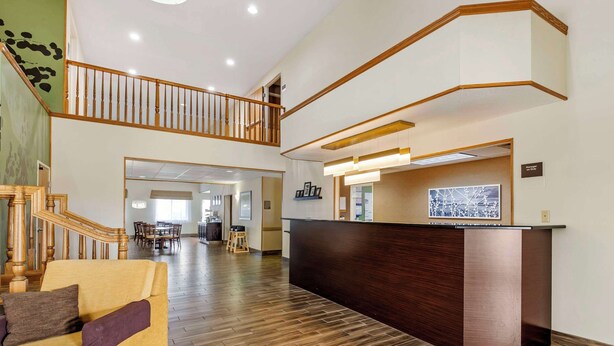 Um hall amplo com balcão de recepção de madeira, escada e área de refeições.