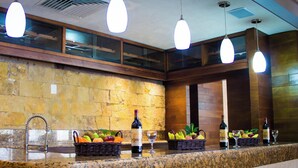 Um saguão de hotel com parede de pedra, balcão de recepção em mármore e luminárias pendentes.