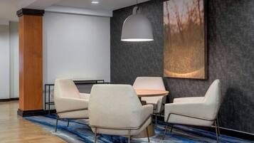 Quarto moderno com mesa redonda, duas cadeiras, luminária pendente e uma grande pintura abstrata na parede.