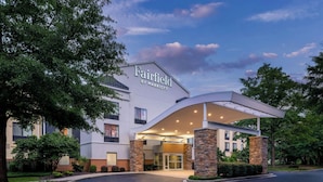 Um hotel Fairfield by Marriott com entrada moderna, pilares de pedra e galeria coberta.