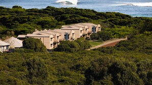 Um hotel à beira-mar, com vários edifícios, rodeado por vegetação densa e o oceano.