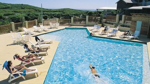 Piscina com cadeiras de descanso e vista para as colinas.