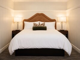 Quarto de hotel com uma cama grande, duas mesas de cabeceira e luminárias.