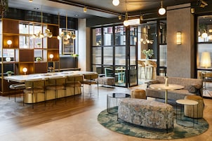 Uma área de estar moderna com bar, sofás e uma grande janela com vista para o exterior.