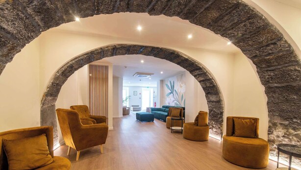 Um hall amplo com arco de pedra, mobiliário moderno e vista para a área de refeições.