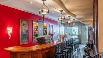 Uma área de bar com balcão de madeira, vários bancos e parede vermelha.