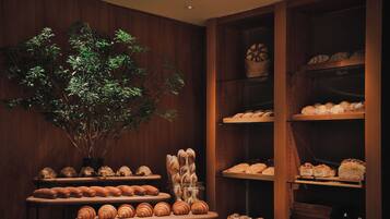 Vitrine de pastelaria com diversos produtos de panificação e um vaso de planta.