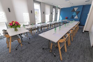 Sala de conferências com uma mesa comprida, cadeiras e garrafas de água.