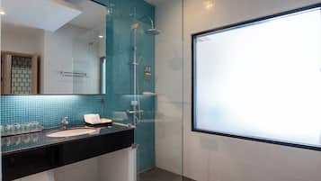 Uma casa de banho moderna com chuveiro de vidro, lavatório preto e espelho grande.