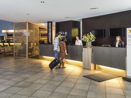Uma área de recepção de hotel com design moderno, incluindo balcão de recepção, espaço de estar e bar.