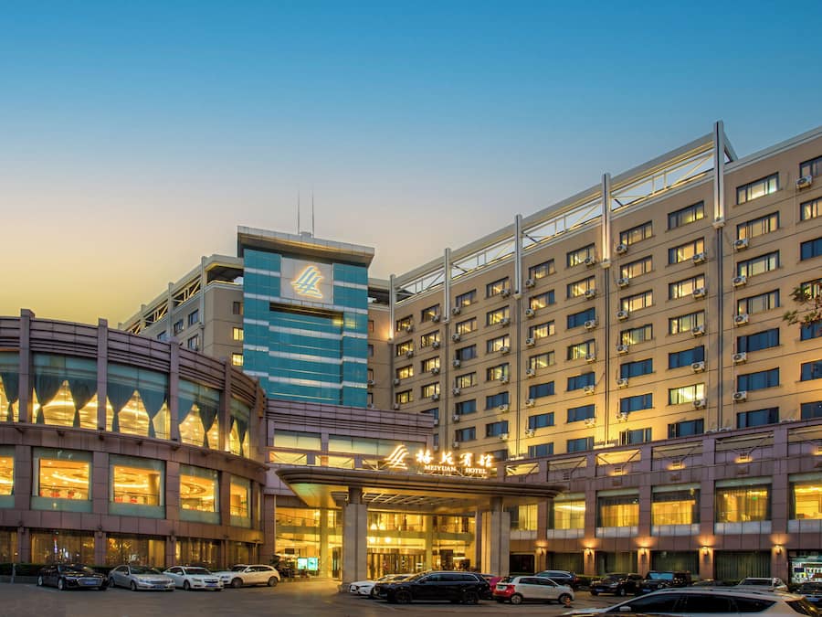 Um hotel com vários andares, entrada destacada, várias varandas e estacionamento.