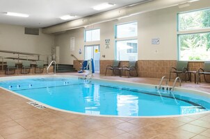 Piscina interior com marcações de pistas claras, uma cadeira de salva-vidas e uma escada de piscina.
