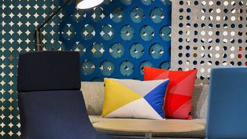 Uma área de estar moderna com parede estampada em azul, uma mesa redonda e duas poltronas.