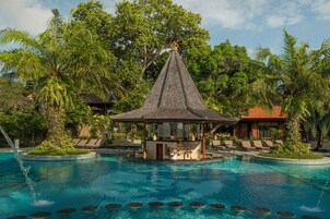 Área de piscina com um gazebo, espreguiçadeiras e paisagem tropical.