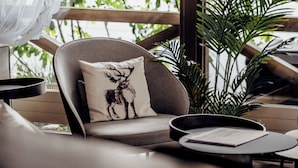 Uma área de estar aconchegante com uma cadeira estofada, uma mesa e uma almofada decorativa.