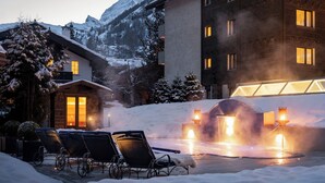 Área externa coberta por neve com cadeiras de lounge e piscina aquecida.