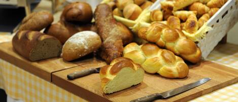 Diversos pães sobre uma tábua de corte de madeira com um faca.