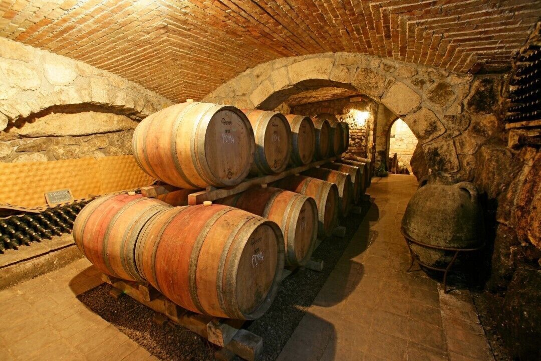 Uma adega com barris de vinho de madeira e paredes de pedra.