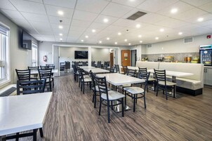Uma sala de jantar moderna com várias mesas e cadeiras, uma área de cozinha e um banco.