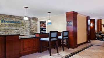 Um saguão de hotel com balcão de recepção, parede de pedra, BridgeMart e área de estar.