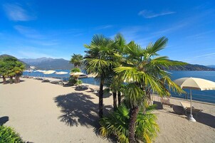 Uma praia com palmeiras, cadeiras de praia e guarda-sóis.