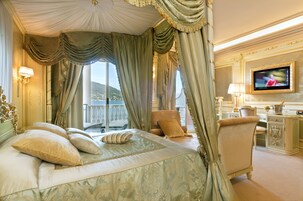 Quarto luxuoso com cama de dossel, televisão e vista para a varanda.