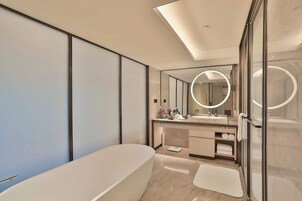 Uma casa de banho moderna com uma banheira grande, um lavatório com espelho e zona de duche.