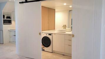Uma cozinha moderna com máquina de lavar, pia e micro-ondas.