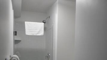 Casa de banho com chuveiro, sanita e porta-toalhas.
