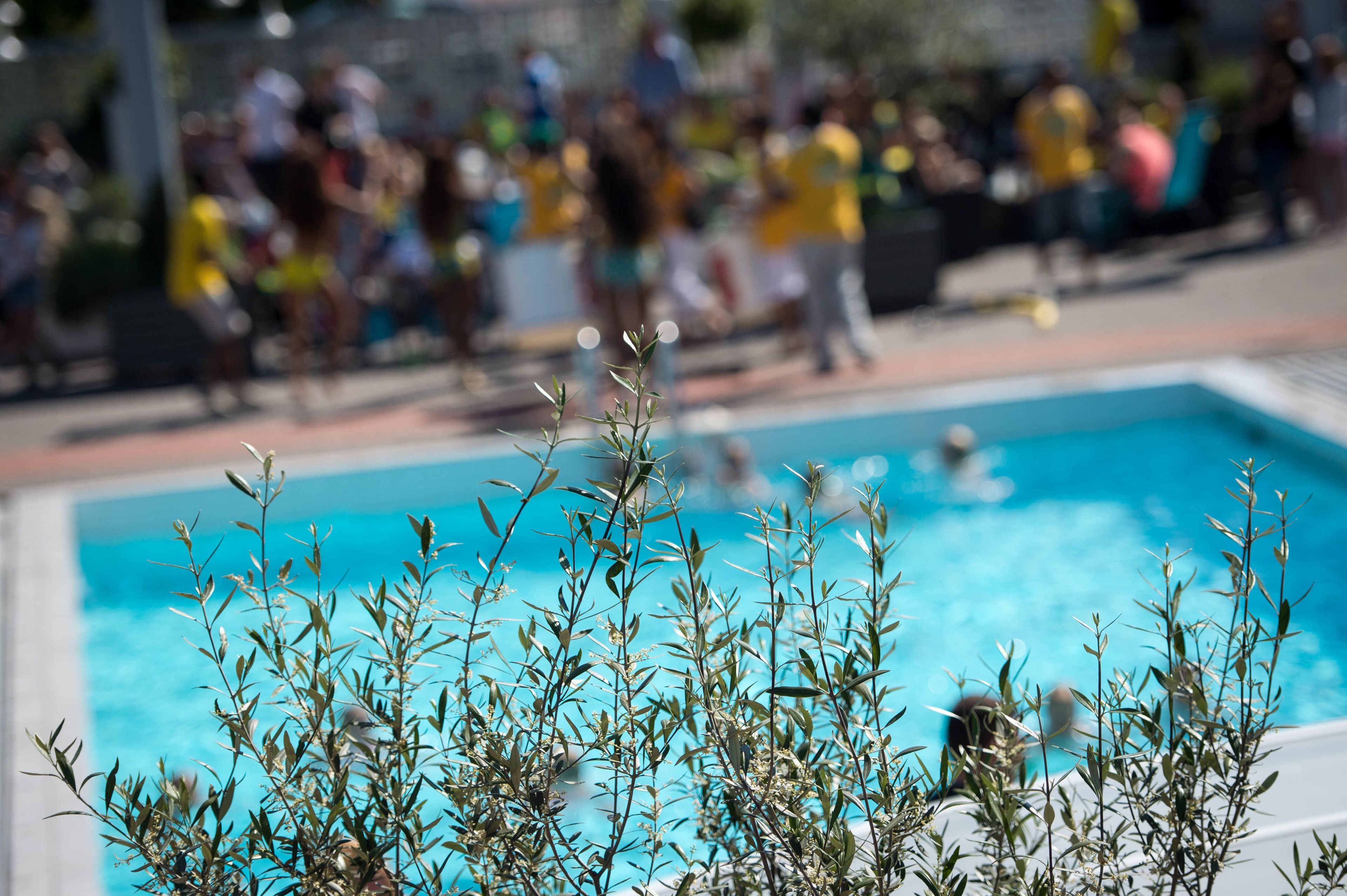 Uma piscina com um grupo de pessoas ao fundo.