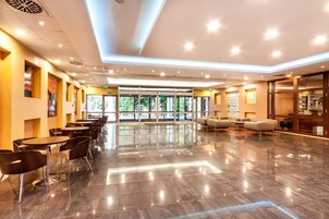 Um hall amplo com piso lustroso, assentos modernos e grandes janelas que proporcionam luz natural.