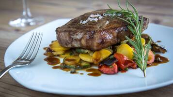 Um prato de bife com legumes e um ramo de alecrim.