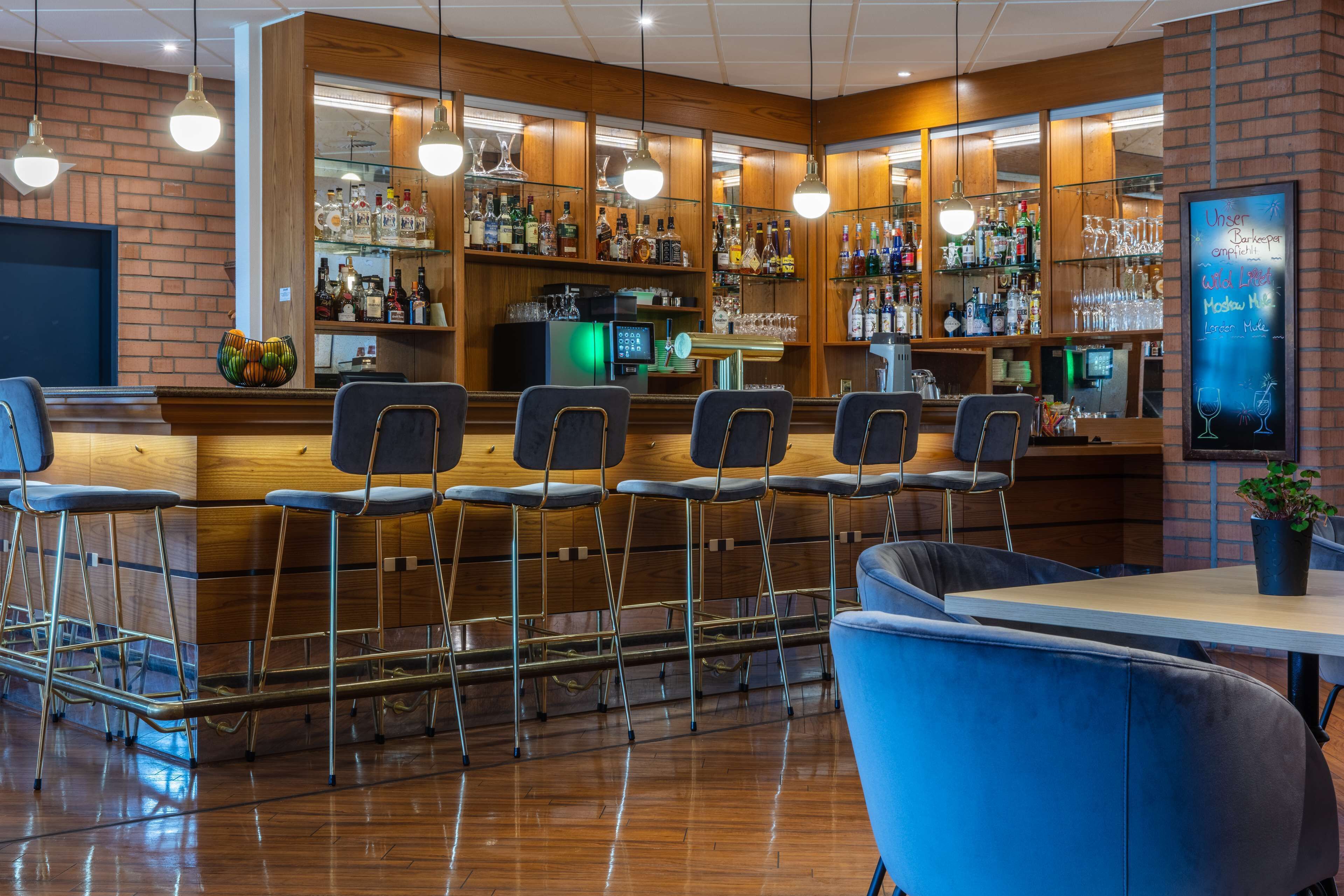 Uma área de bar com balcões de madeira, vários bancos e um espaço de estar com mesa e cadeiras.