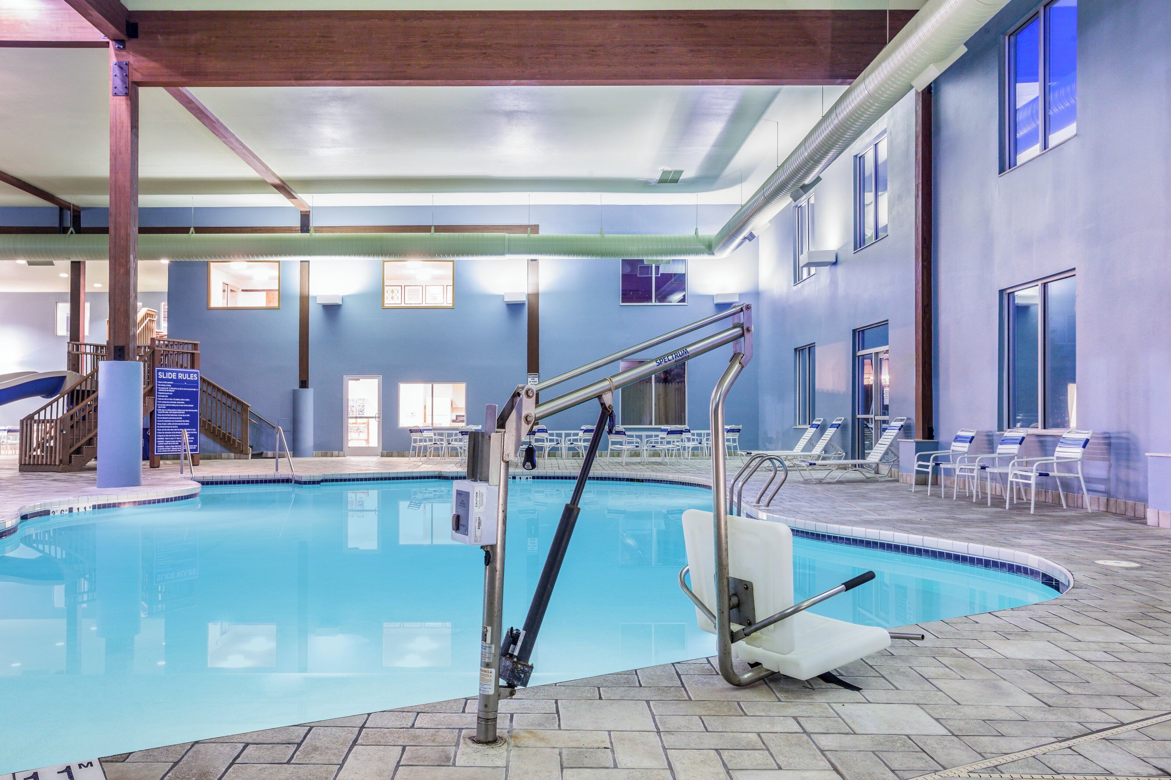 Piscina interna com trampolim, espreguiçadeiras e escadaria para um nível superior.