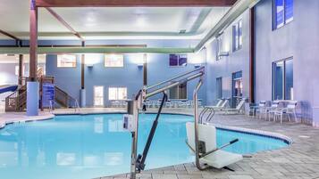 Piscina interna com trampolim, espreguiçadeiras e escadaria para um nível superior.