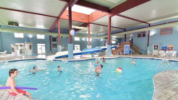 Uma piscina interior com várias pistas de natação, um escorrega e uma área de recreação.