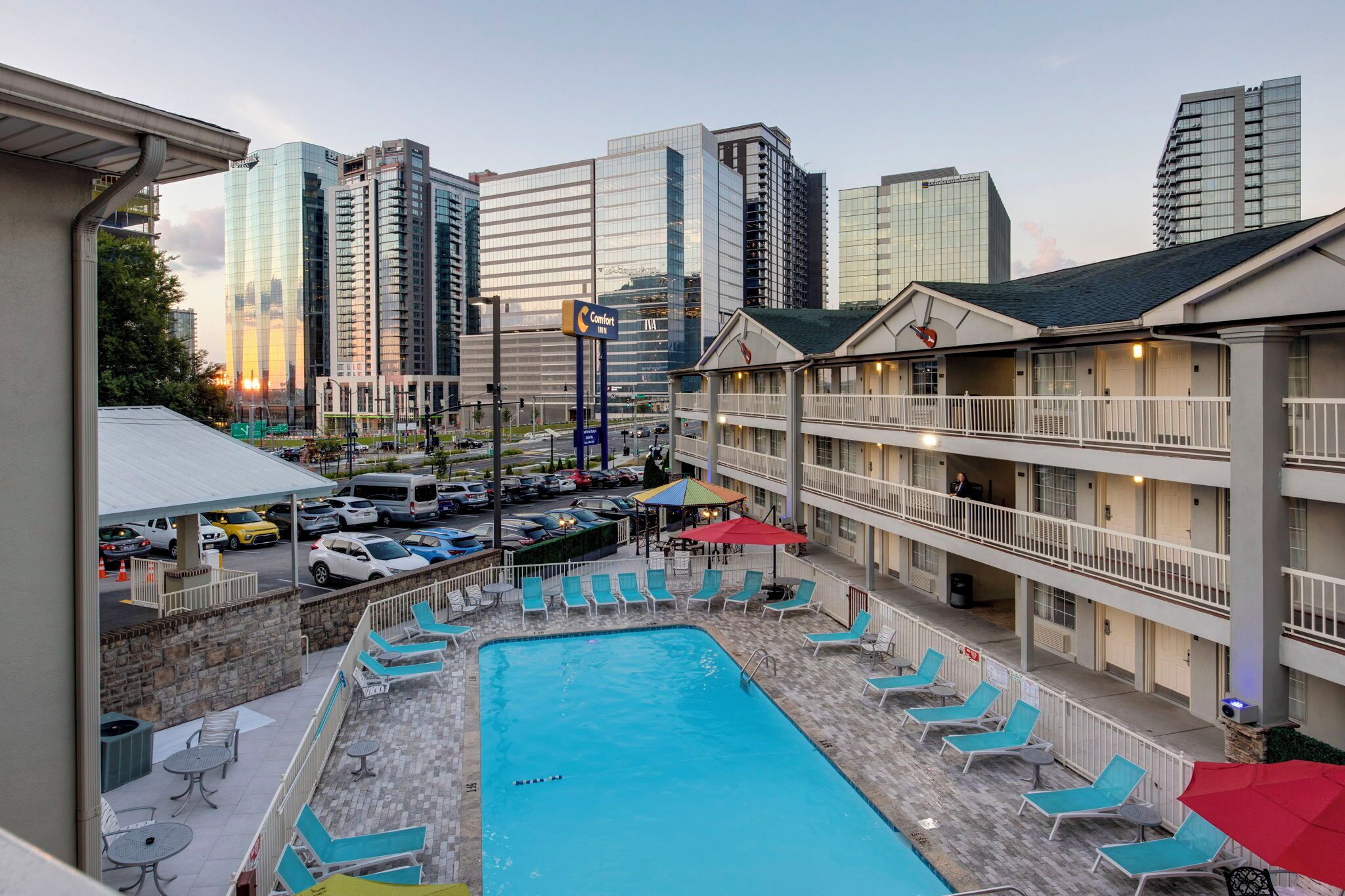 Um hotel com piscina no terraço, várias varandas e vista para edifícios altos.