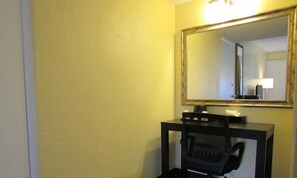 Quarto de hotel com um espelho grande, uma escrivaninha e uma cadeira.