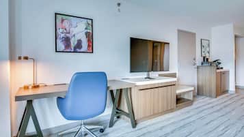 Quarto de hotel moderno com uma escrivaninha, cadeira e um espelho grande.